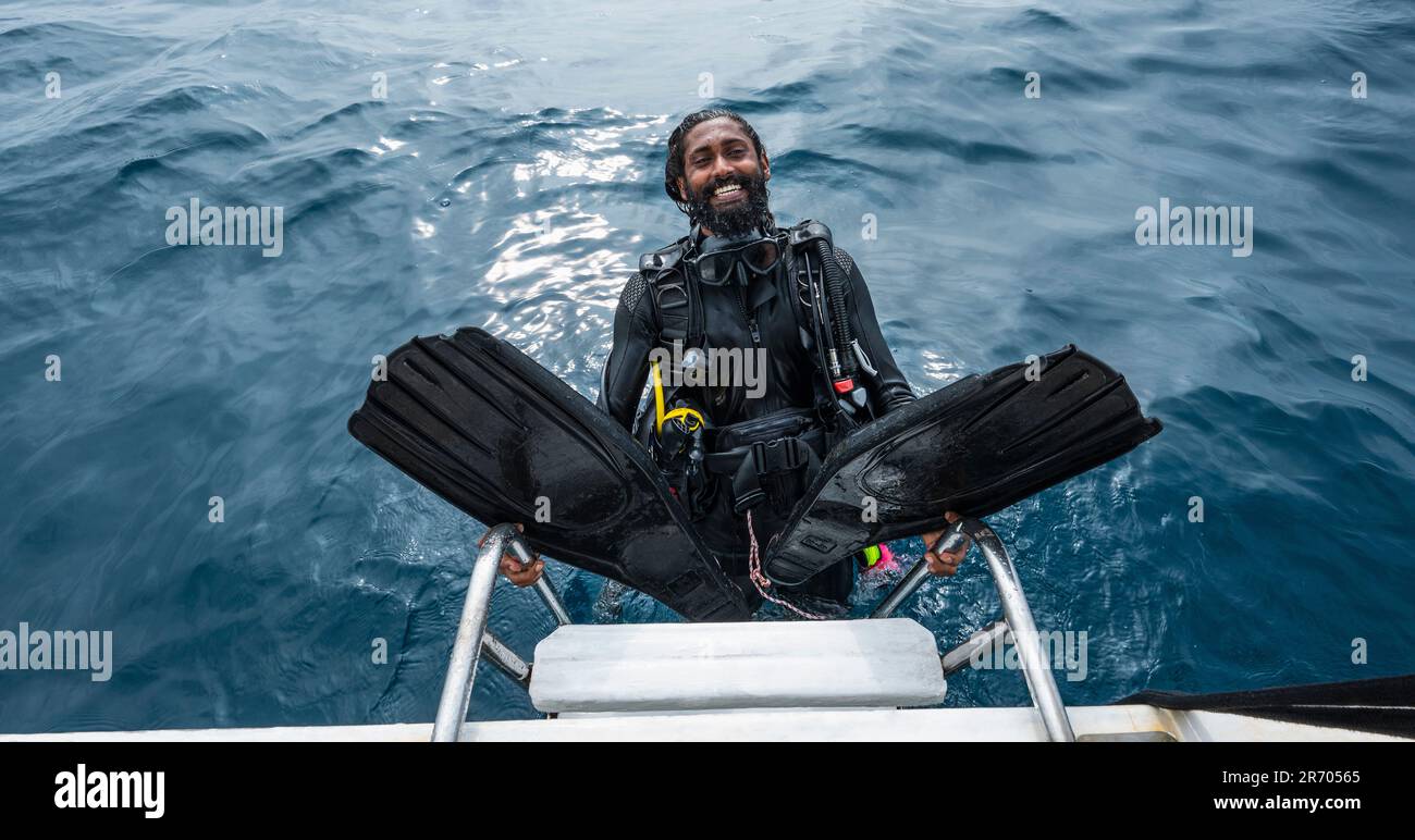 diver climbing up to a boat after finishing a dive in the Maldives ...