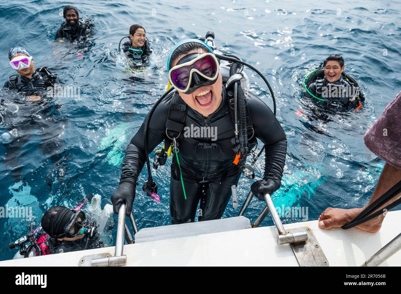 diver climbing up to a boat after finishing a dive in the Maldives ...