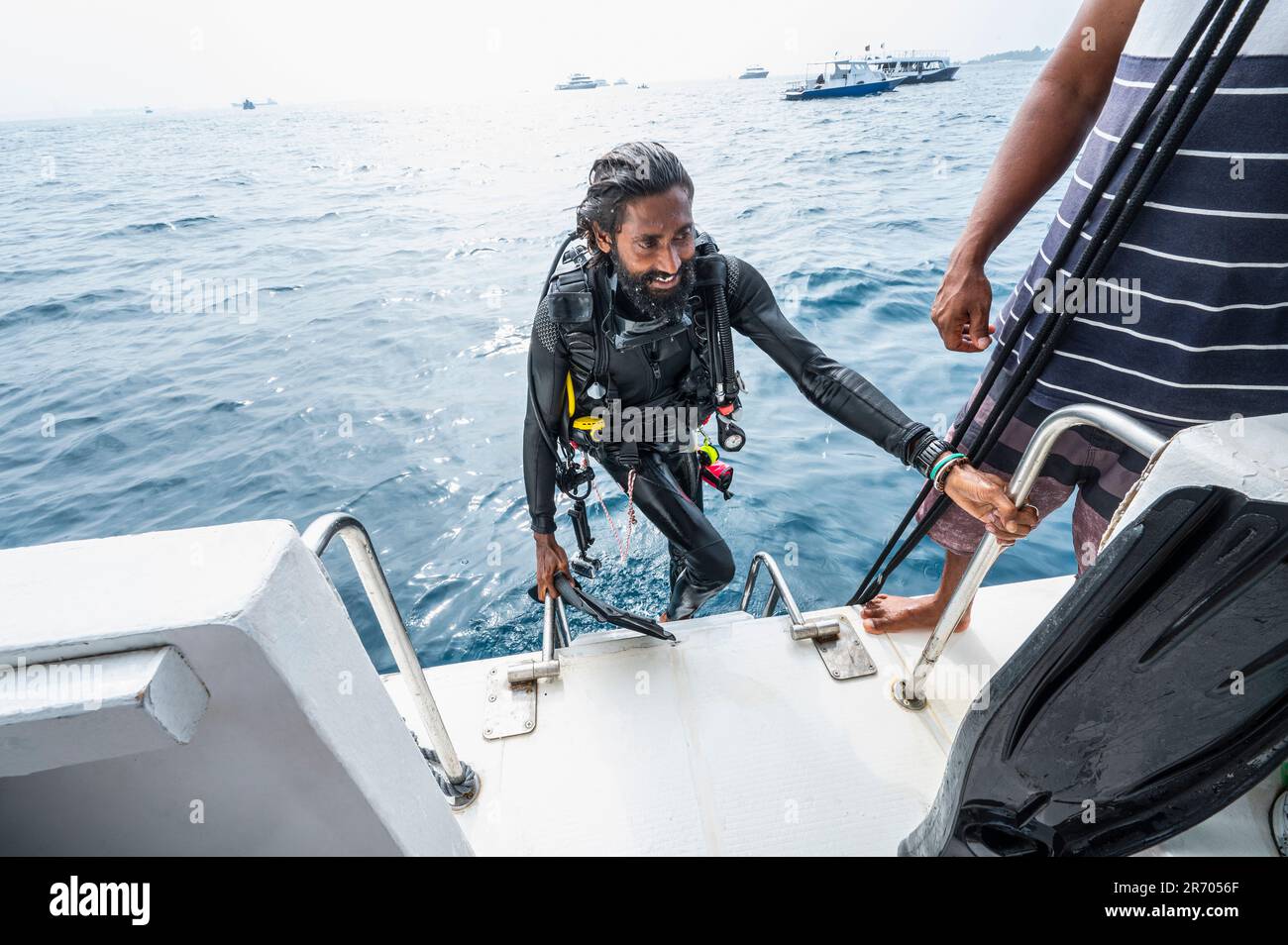 diver climbing up to a boat after finishing a dive in the Maldives ...