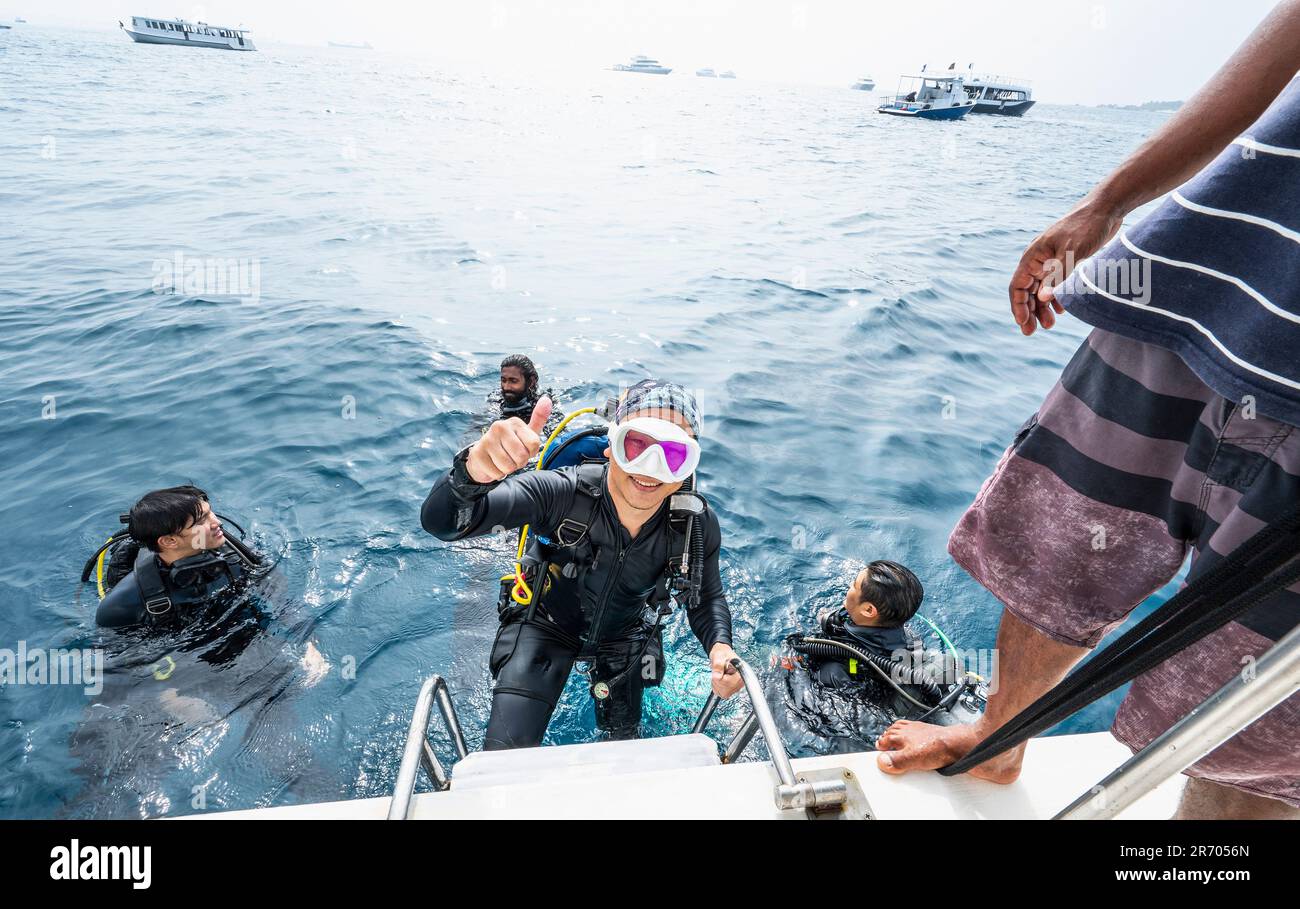 diver climbing up to a boat after finishing a dive in the Maldives ...