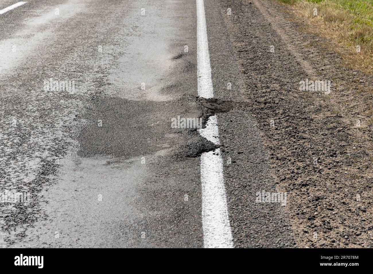 A damaged road dangerous for traffic, pits and cracks on the asphalt of ...