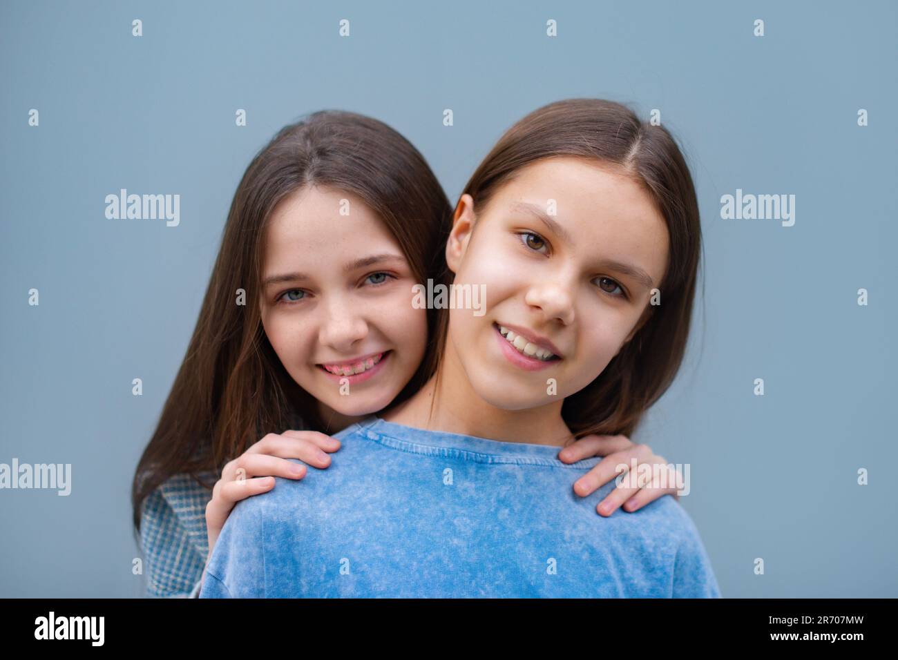 Two Teenage Girls Looking To Camera And Smile On Blue Background One Girl With Colorful Braces