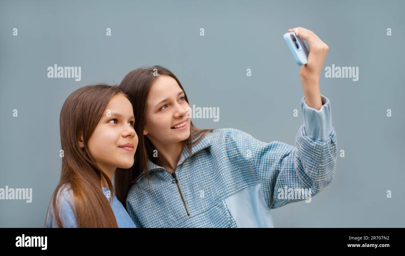 Two young smiling girls taking selfie self portrait photos on ...