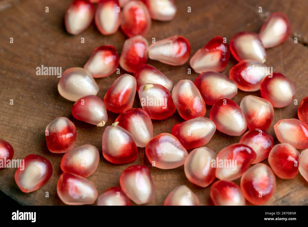 Red pomegranate seeds on the table and the board, scattered pomegranate ...