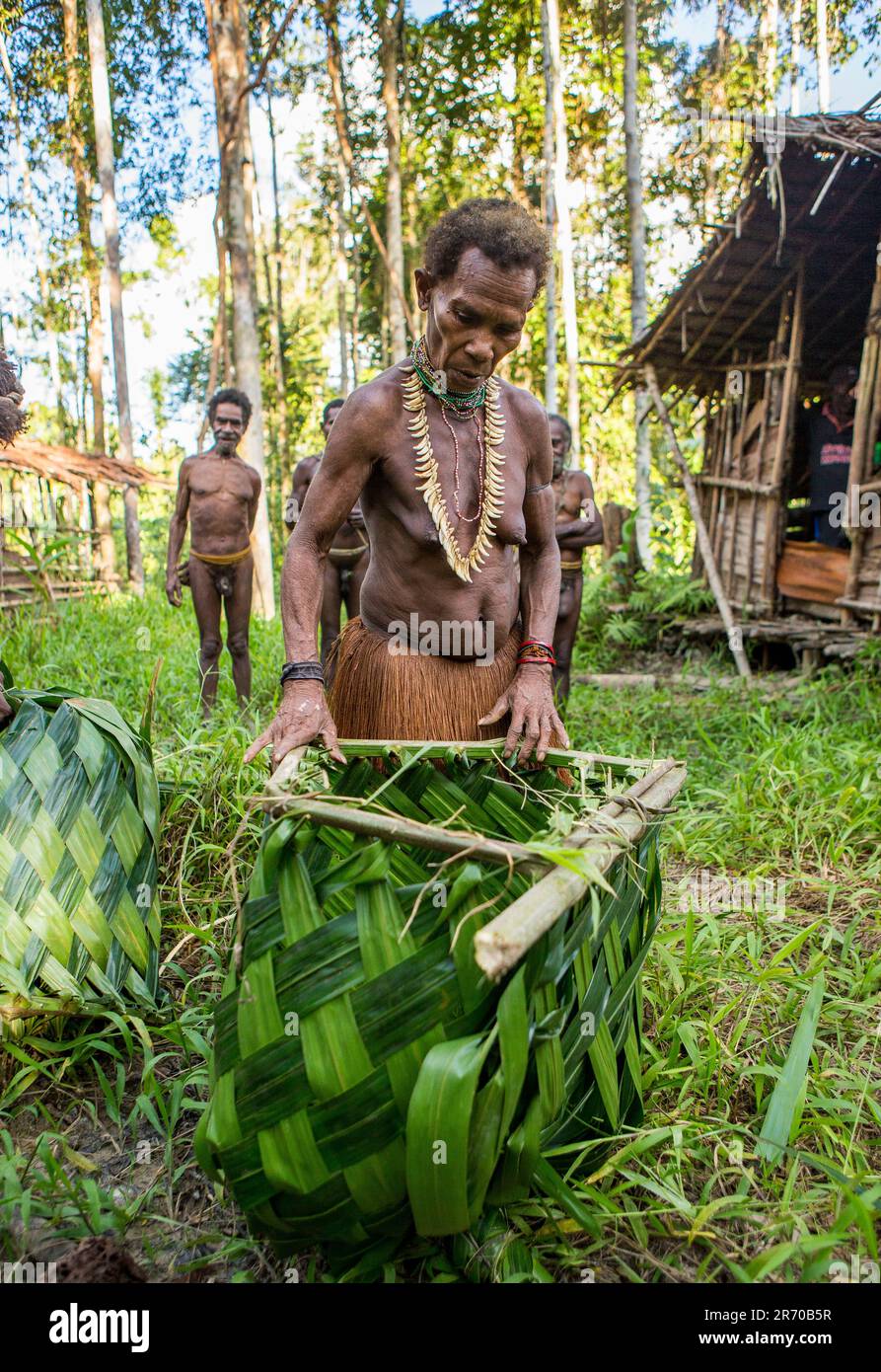 Women of the Korowai tribe are weaving fishing baskets. Tribe of ...