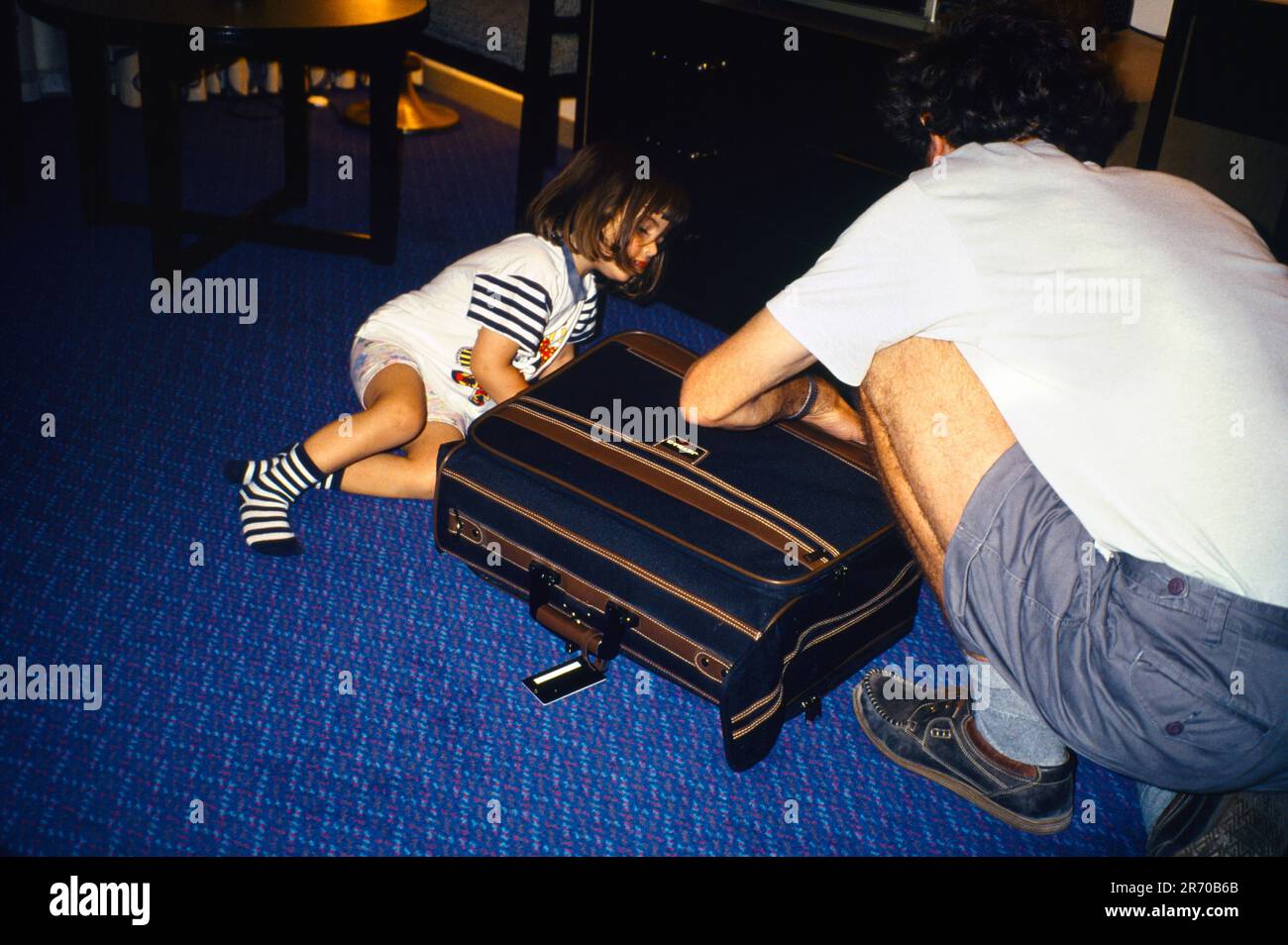 Young Child Helping Father Zip up Overloaded Suitcase ready for a ...