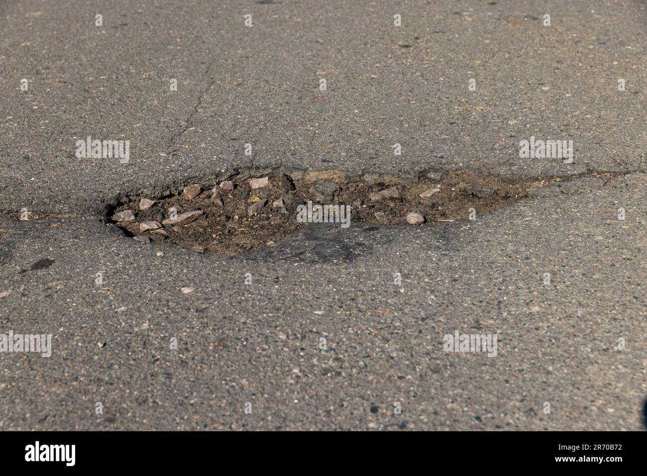 A damaged road dangerous for traffic, pits and cracks on the asphalt of ...