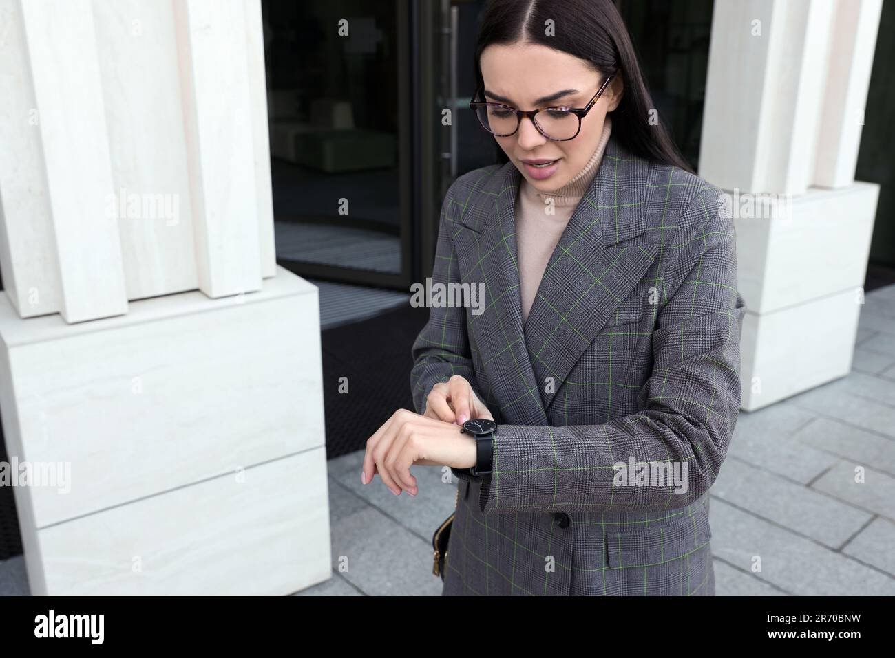 Emotional woman checking time on watch outdoors. Being late concept ...