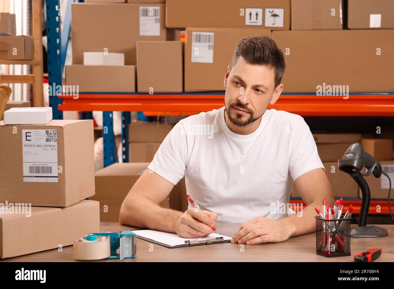Post office worker with clipboard and parcels at counter indoors Stock ...