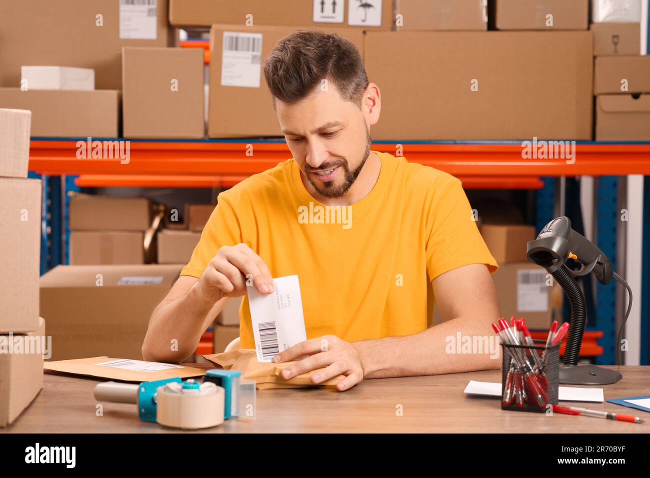 Post office worker sticking barcode on parcel at counter indoors Stock ...