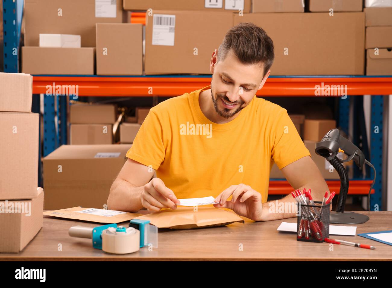 Post office worker sticking barcode on parcel at counter indoors Stock ...