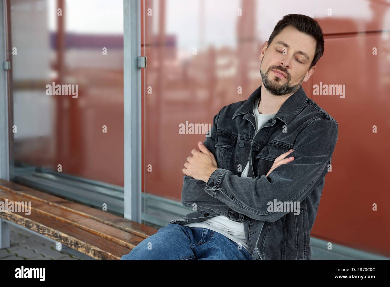 Tired man sleeping at public transport stop outdoors Stock Photo - Alamy