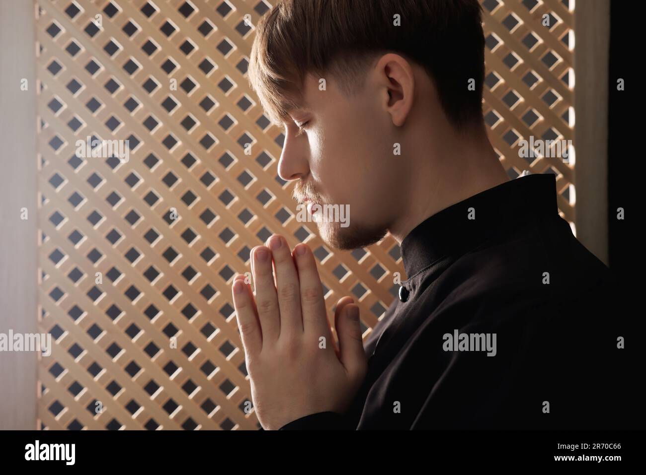 Catholic priest praying near wooden window in confessional booth Stock ...