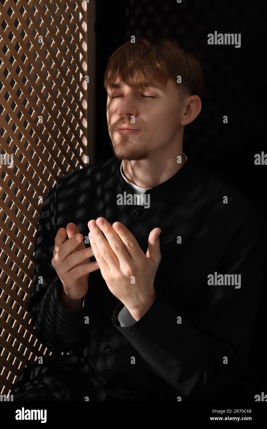Catholic priest praying near wooden window in confessional booth Stock ...