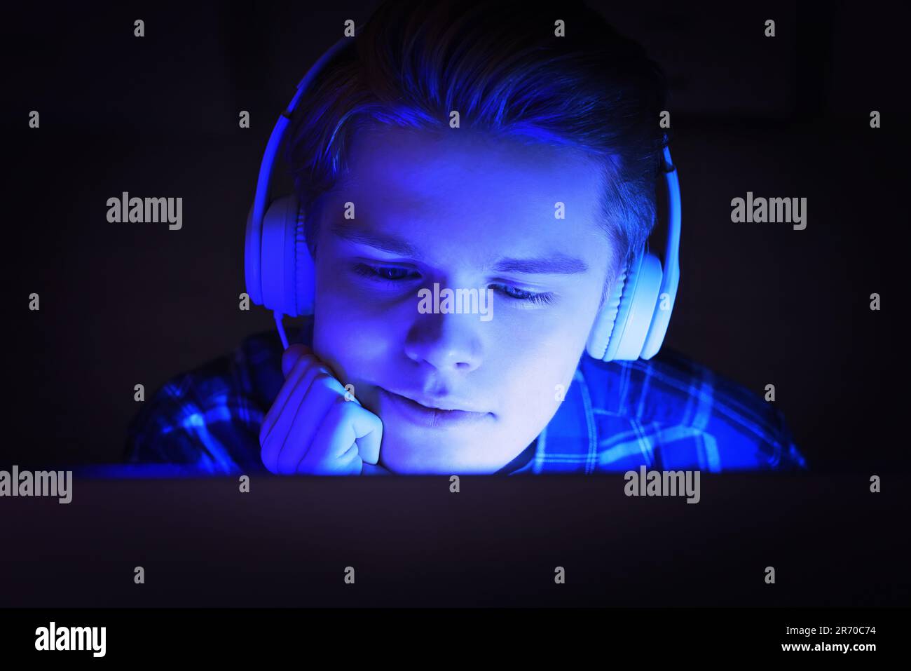 Internet addiction. Teenage boy in headphones using device at night ...