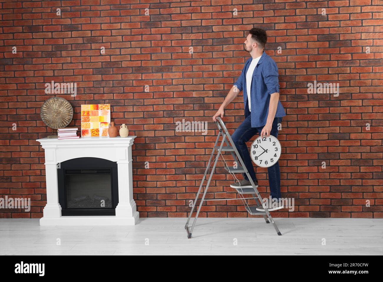 Man on stepladder hanging clock at home Stock Photo - Alamy