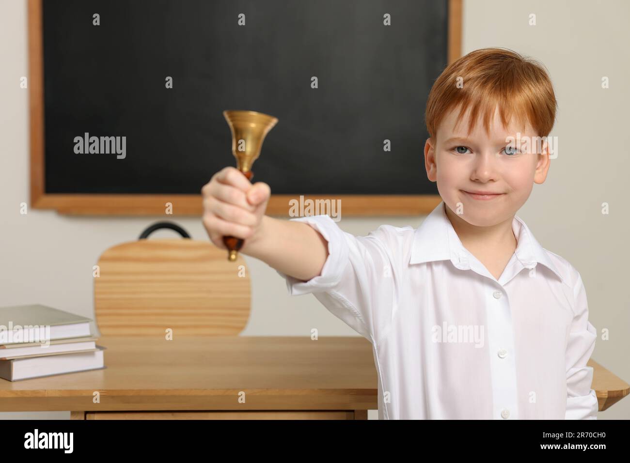 Cute little boy ringing school bell in classroom Stock Photo - Alamy