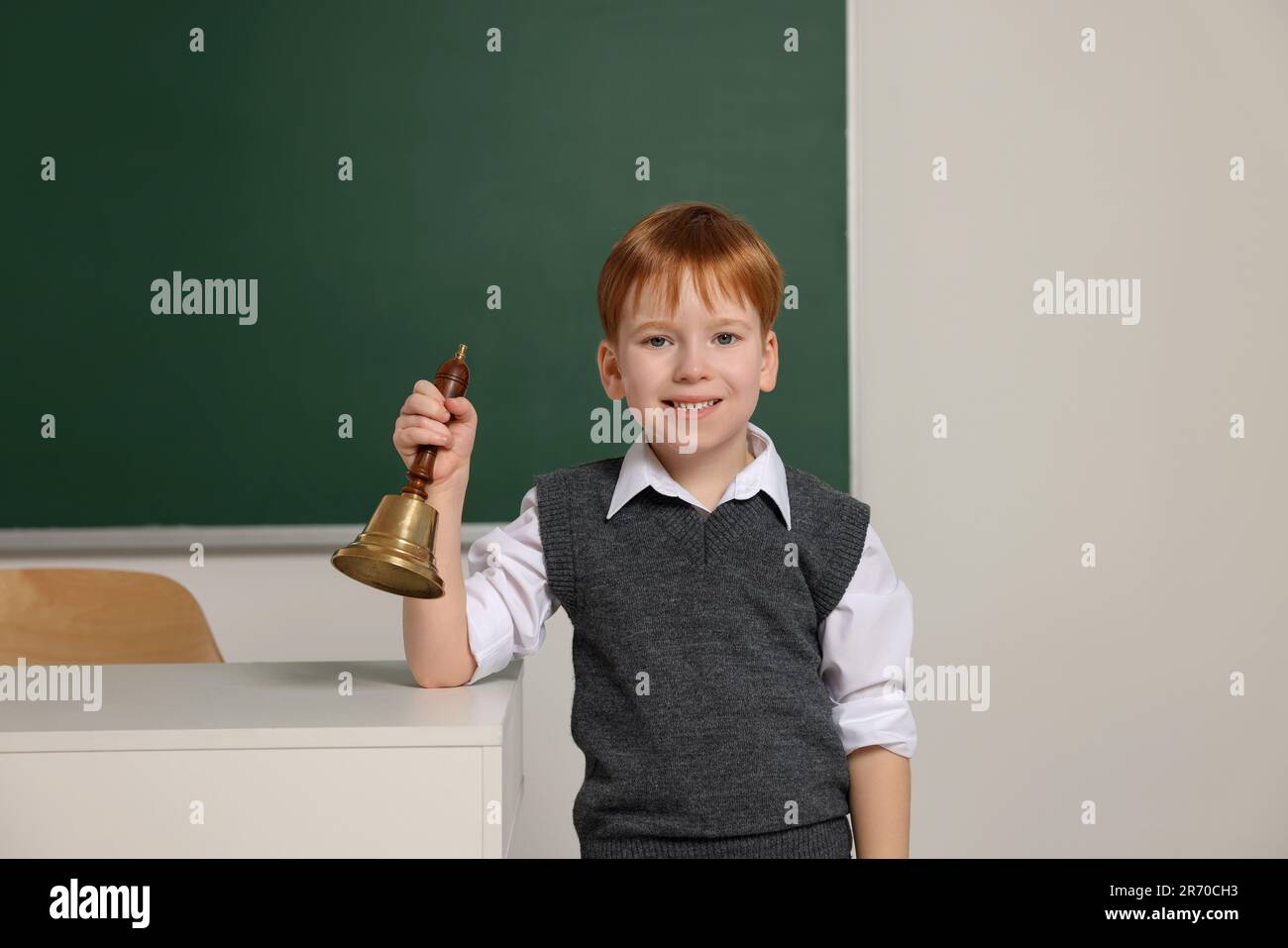 Cute little boy ringing school bell in classroom Stock Photo - Alamy