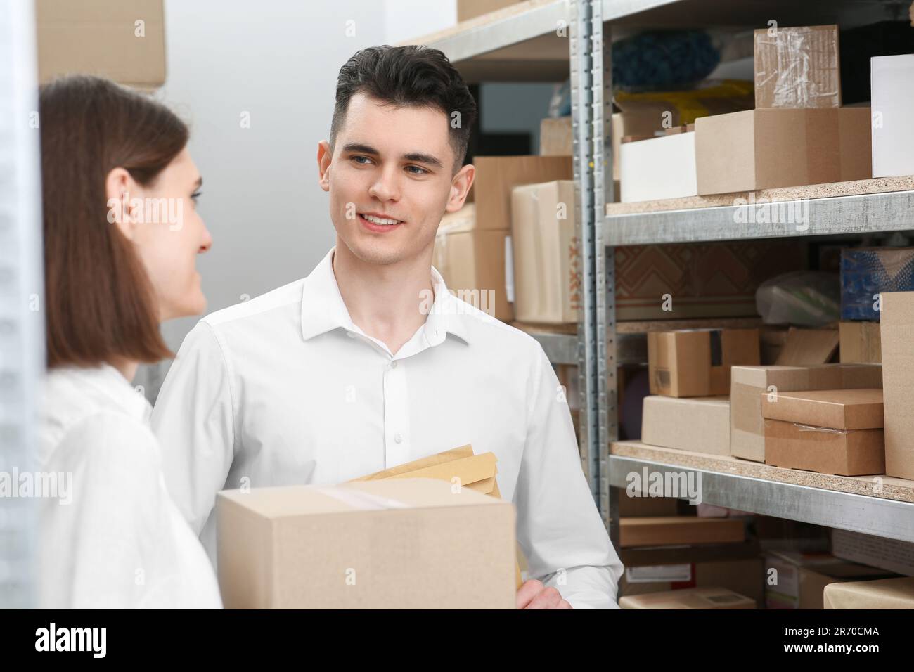 Post office workers with parcels near rack indoors Stock Photo - Alamy
