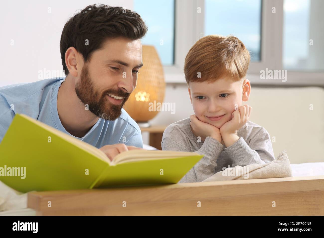 Father reading book with his child on bed at home Stock Photo - Alamy
