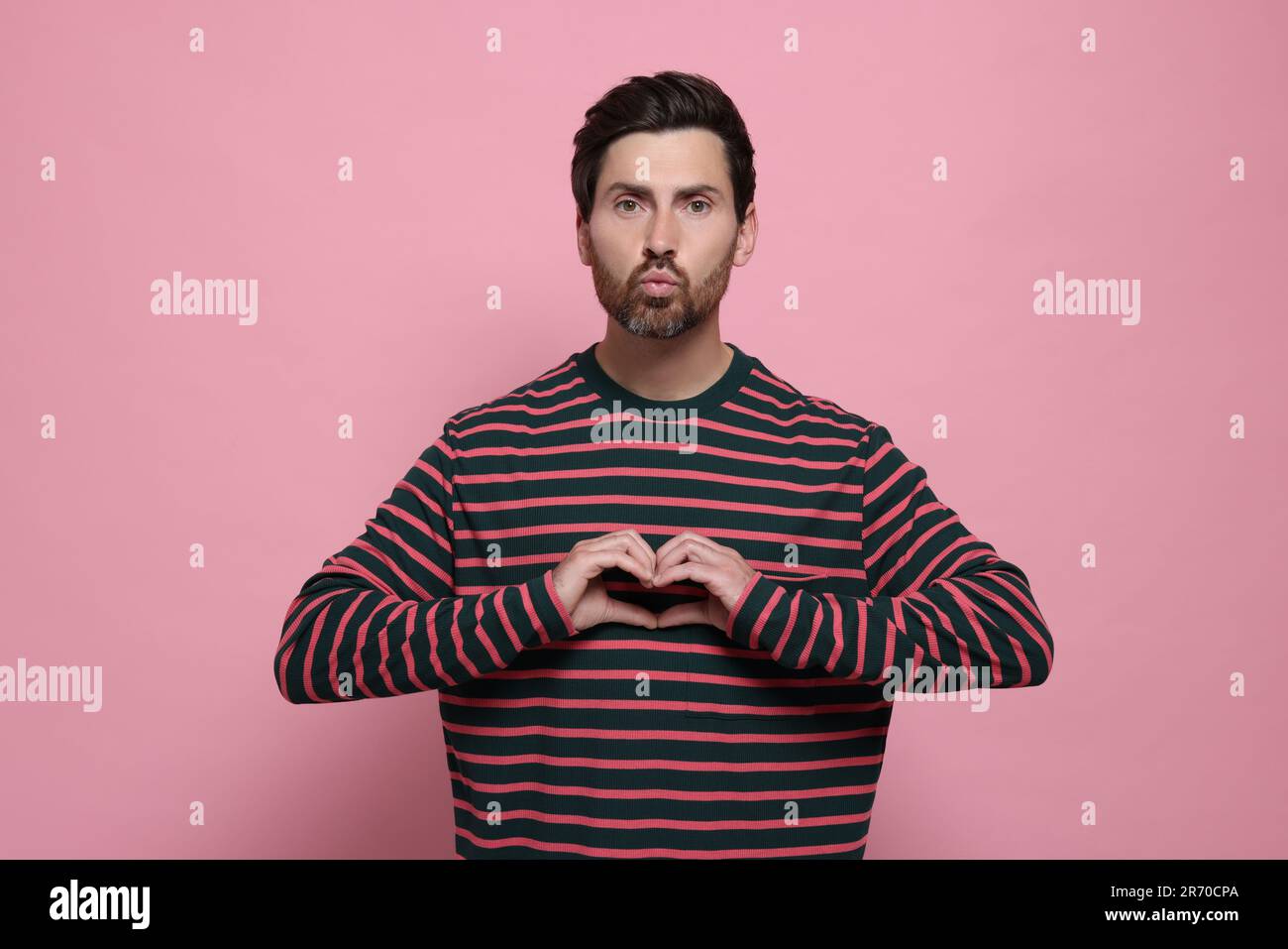 Handsome man making heart with hands and blowing kiss on pink ...