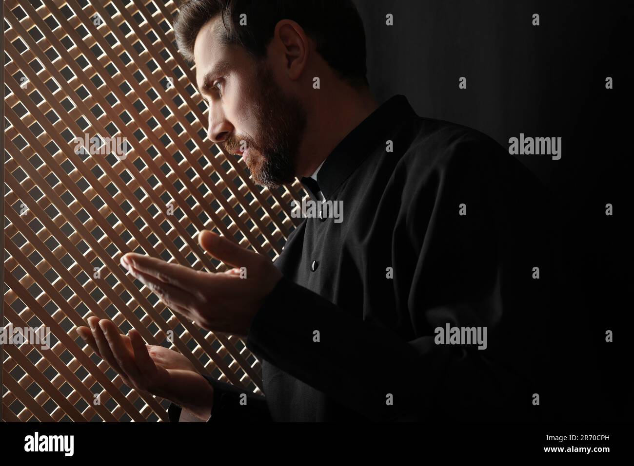 Catholic priest in cassock talking to parishioner in confessional Stock ...