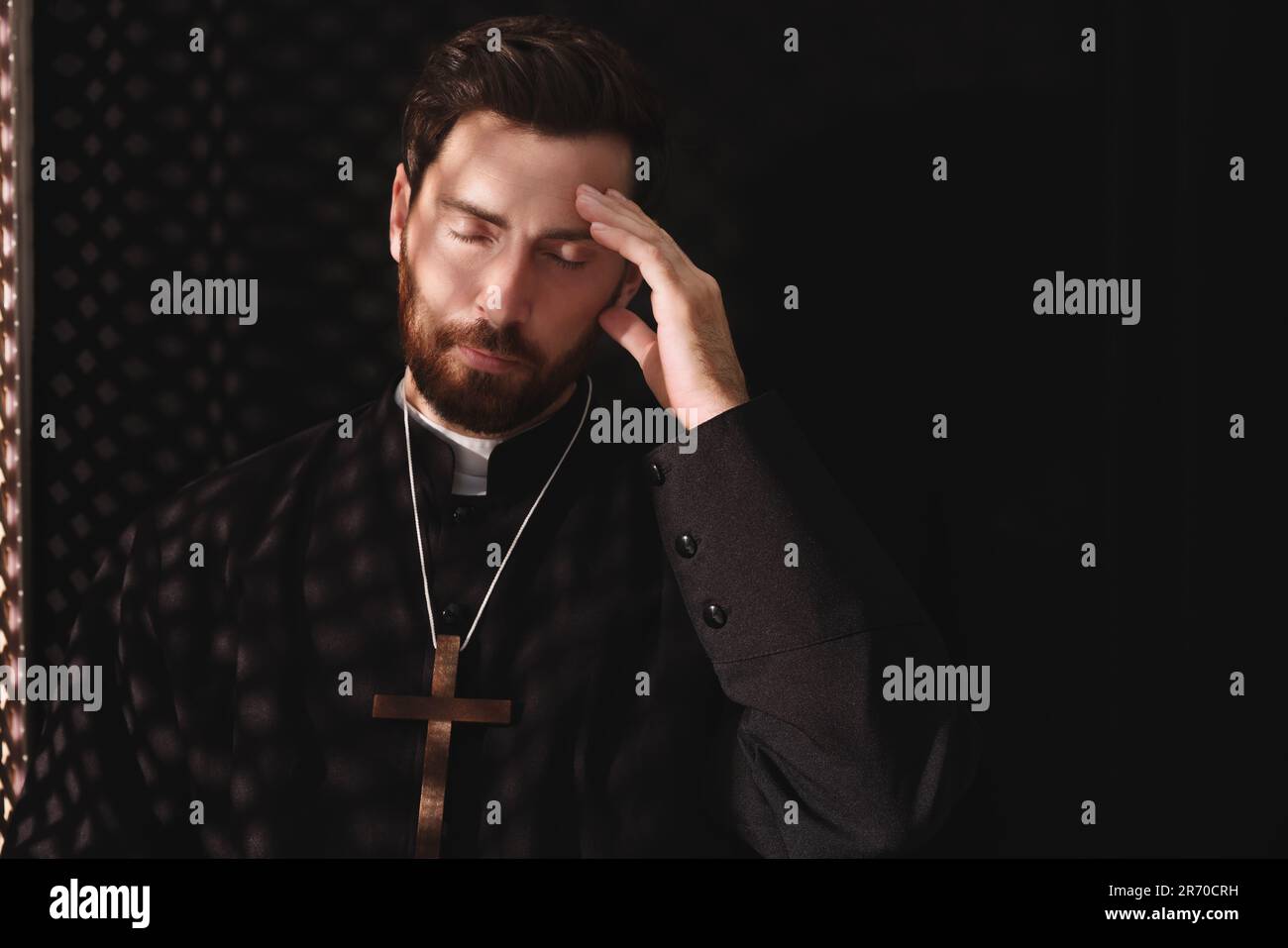 Catholic priest wearing cassock in confessional booth Stock Photo - Alamy