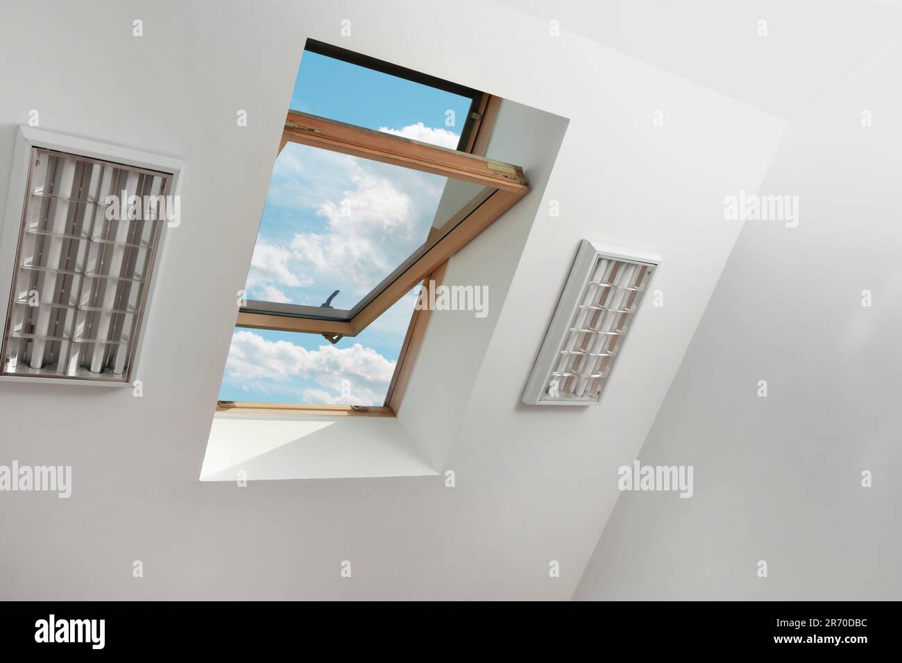 Open skylight roof window on slanted ceiling in attic room, low angle ...