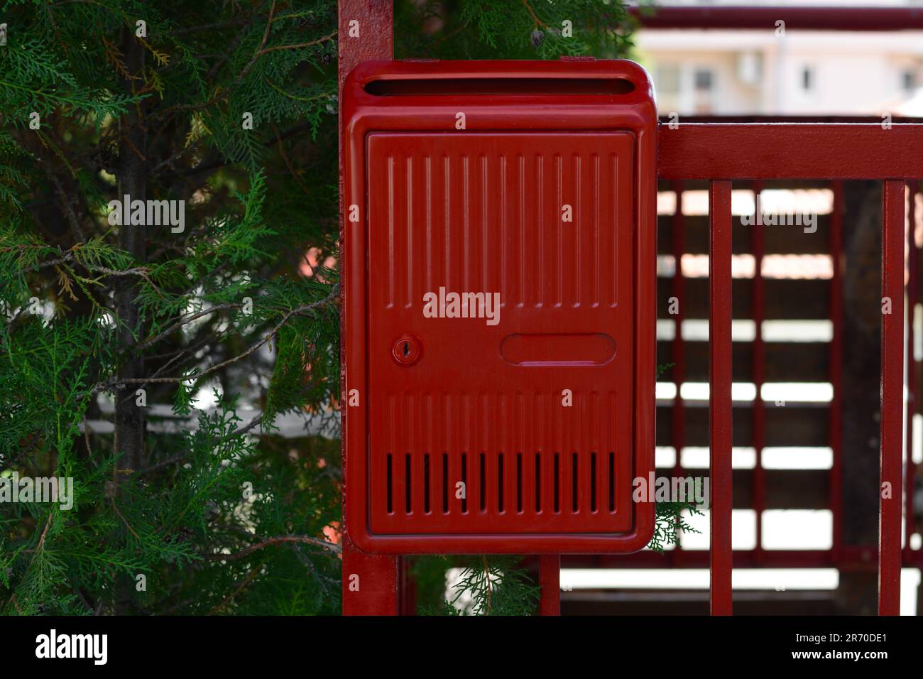 Red beautiful metal letter box near tree outdoors Stock Photo - Alamy