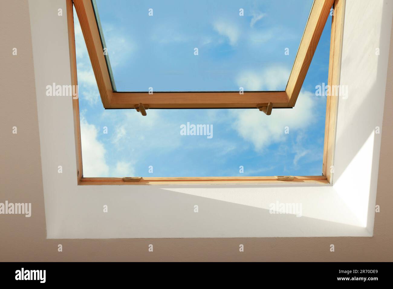 Open skylight roof window on slanted ceiling in attic room, bottom view ...