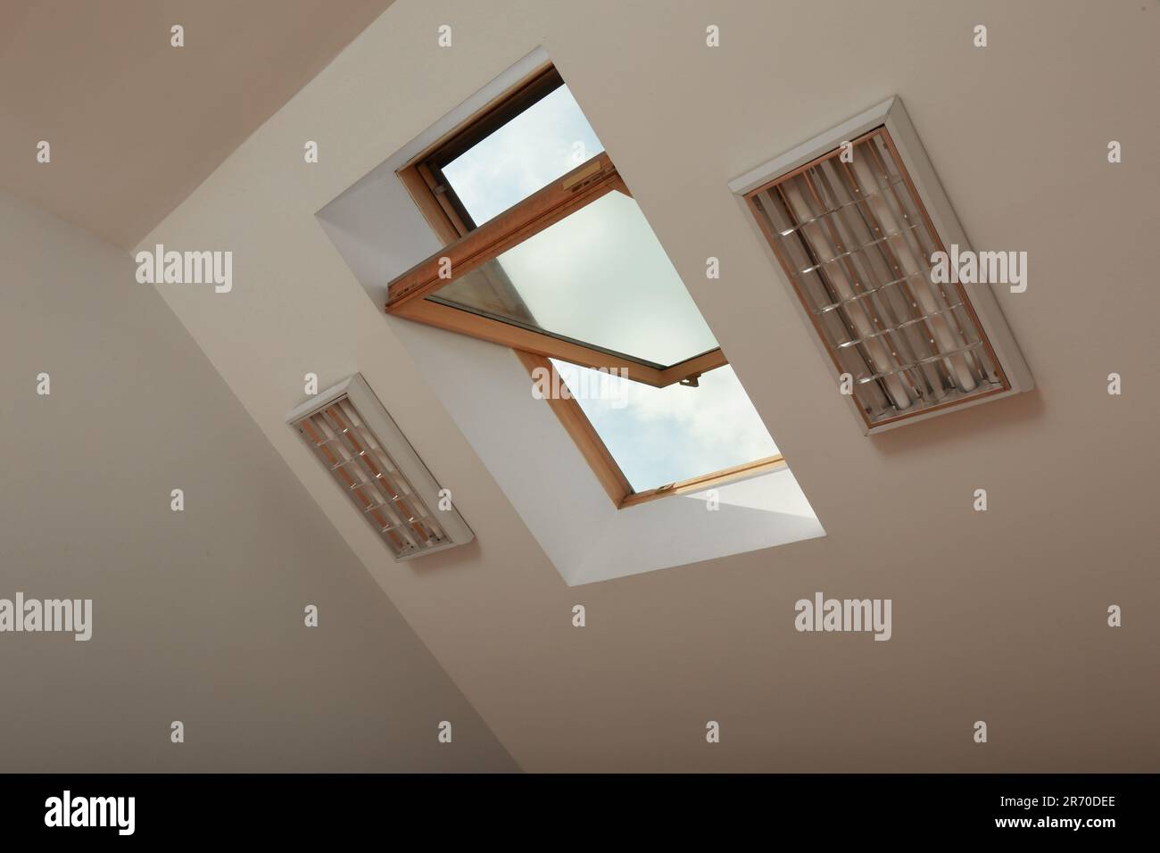 Open skylight roof window on slanted ceiling in attic room, low angle ...
