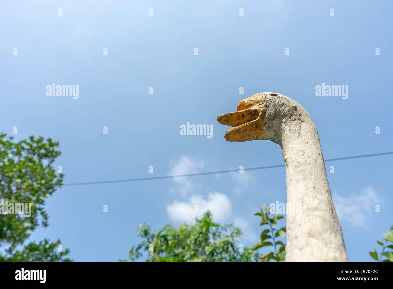 A white swan statue under a sky blue is seen from below. Swan statue ...