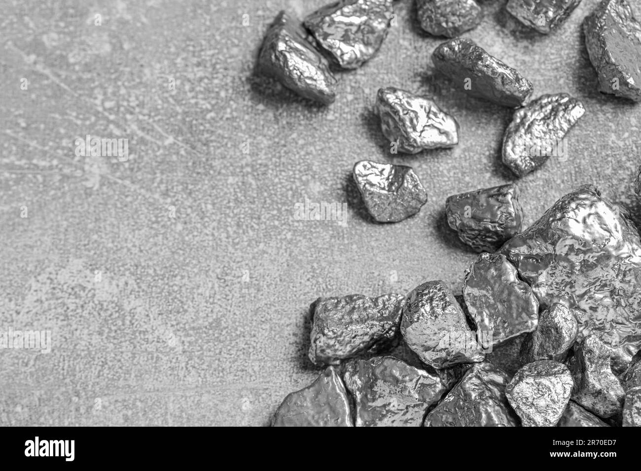 Pile of silver nuggets on light grey table, above view. Space for text ...