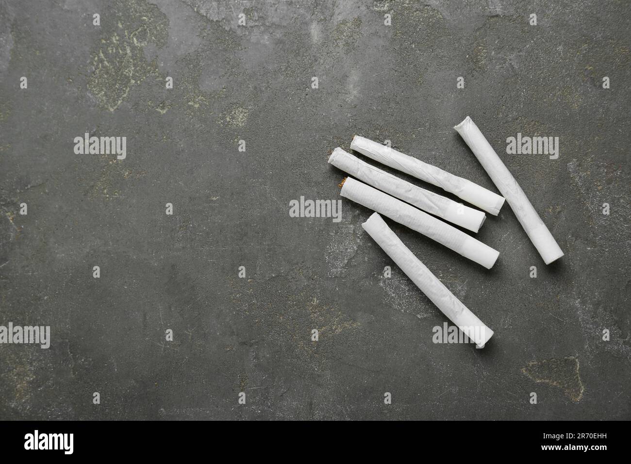 Hand rolled cigarettes with tobacco on dark grey background, flat lay ...
