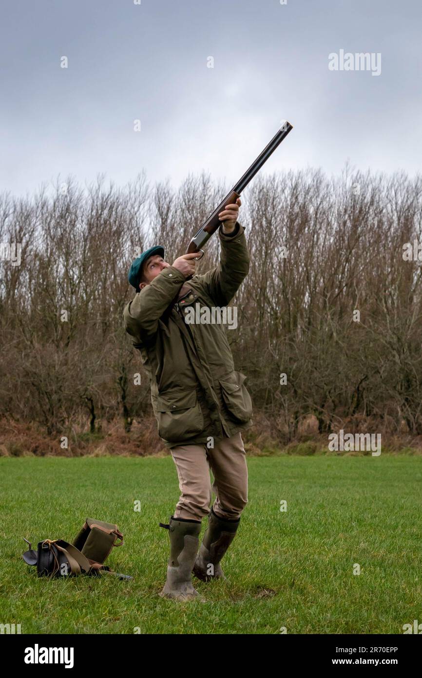 A Caucasian male stands with a raised firearm in his hands, pointing ...