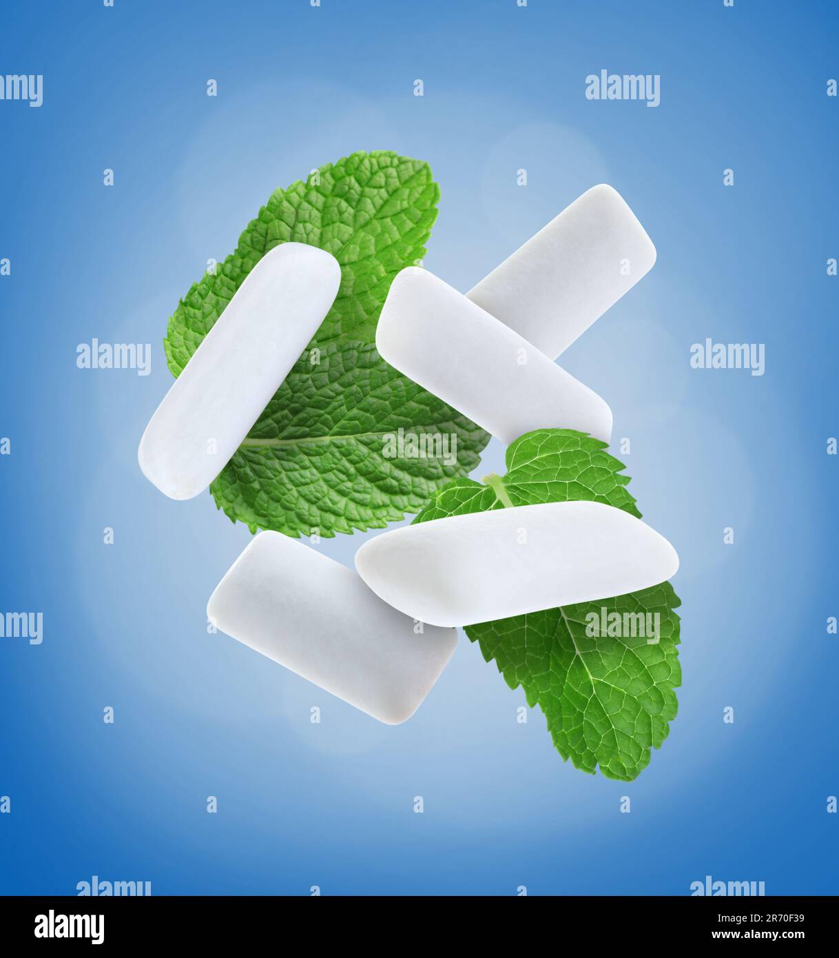 Fresh mint leaves and chewing gum pads falling on blue background Stock ...