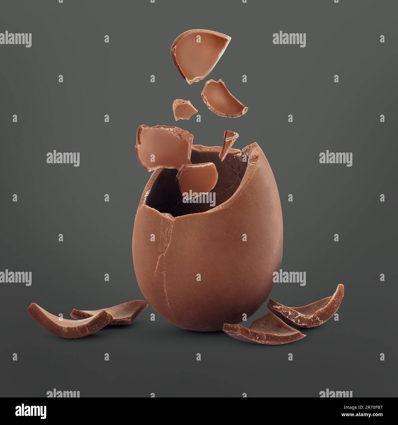 Exploded milk chocolate egg on dark grey background Stock Photo - Alamy