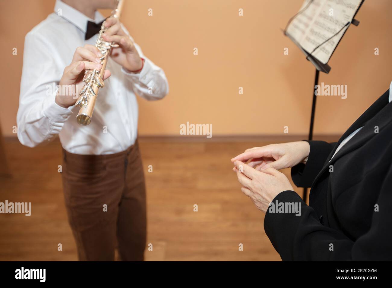 A music teacher listens to a student playing the flute in a music ...