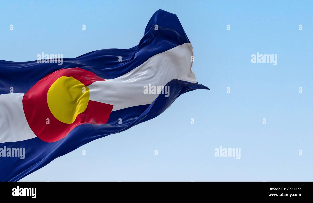 Colorado state flag waving in the wind on a clear day. Three blue ...