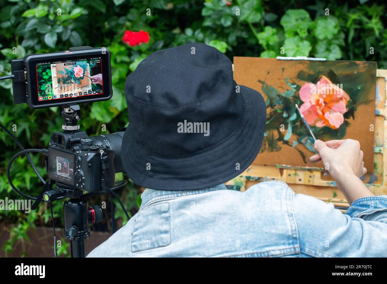 A male painter artist is using his camera to film his painting process ...