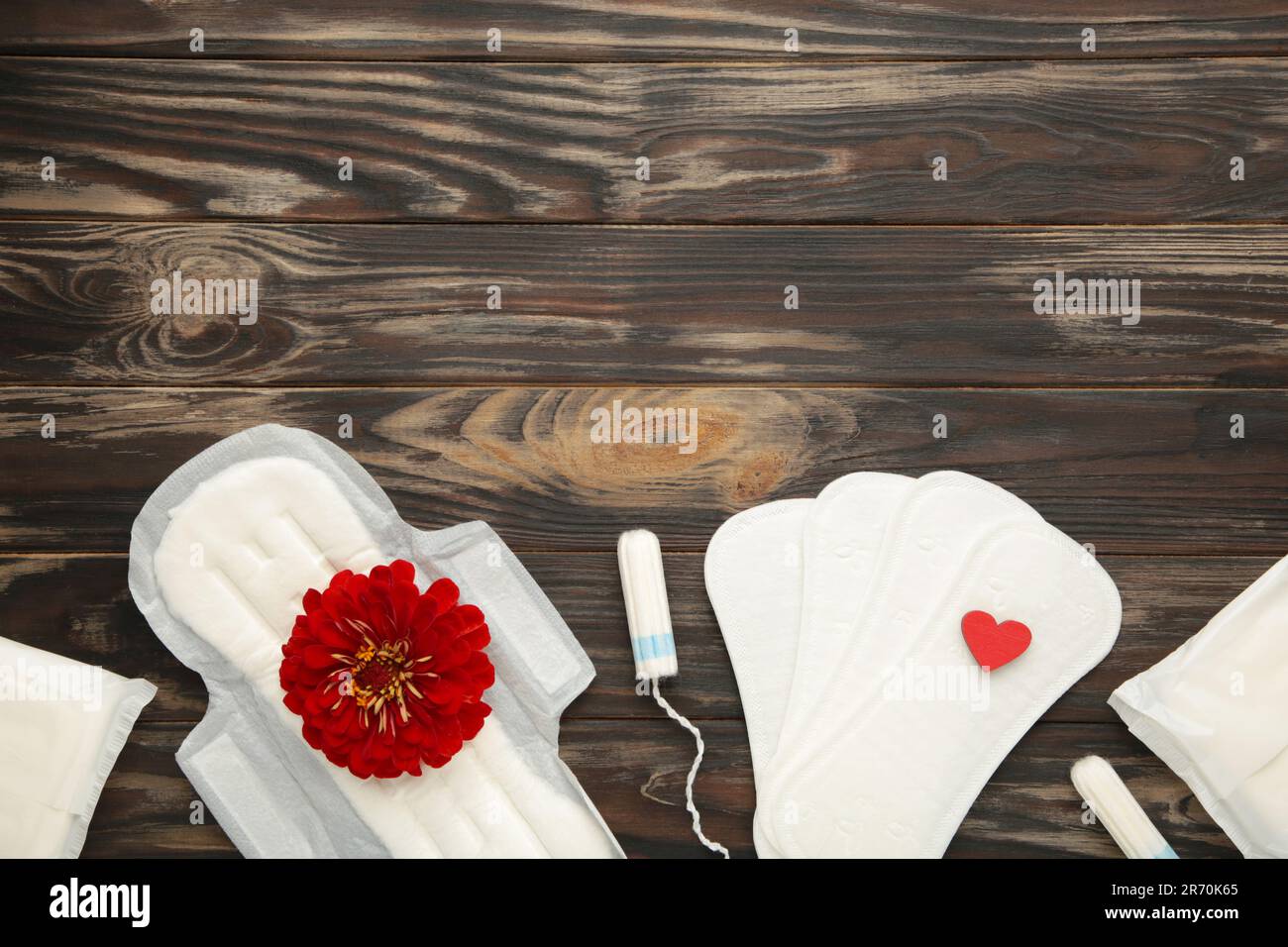 Menstrual tampons and pads on brown background. A rose flower lies on a ...
