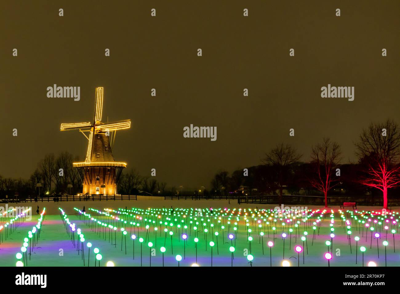 Silhouette of a windmill against a starlit night sky, illuminated by a ...