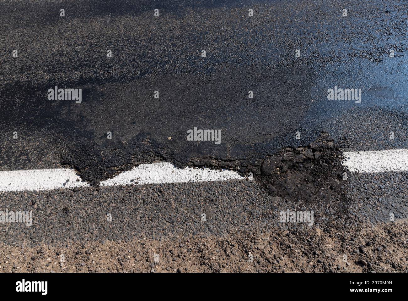 A damaged road dangerous for traffic, pits and cracks on the asphalt of ...