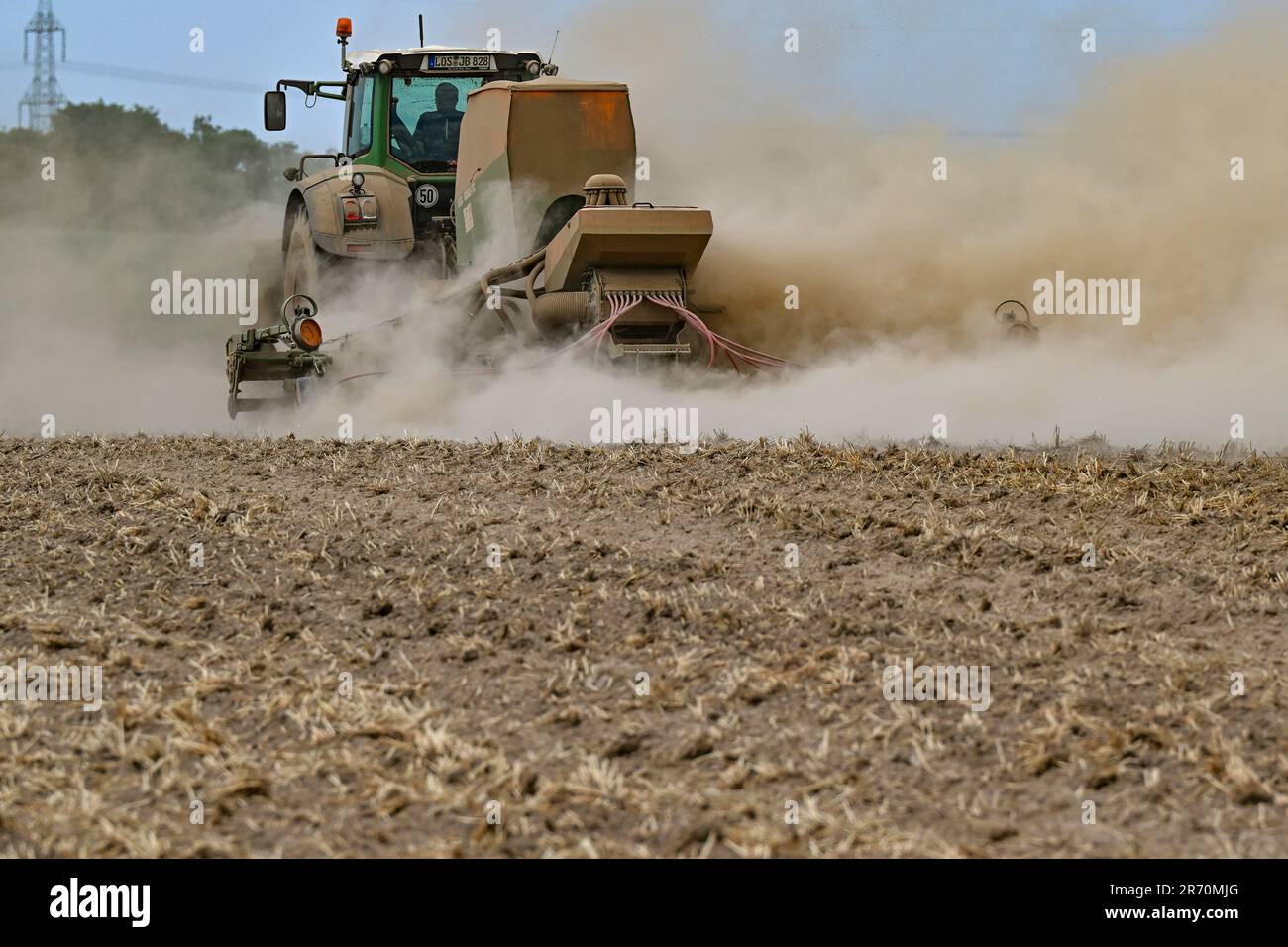 A farmer drills seed into the parched field, kicking up a lot of dust ...