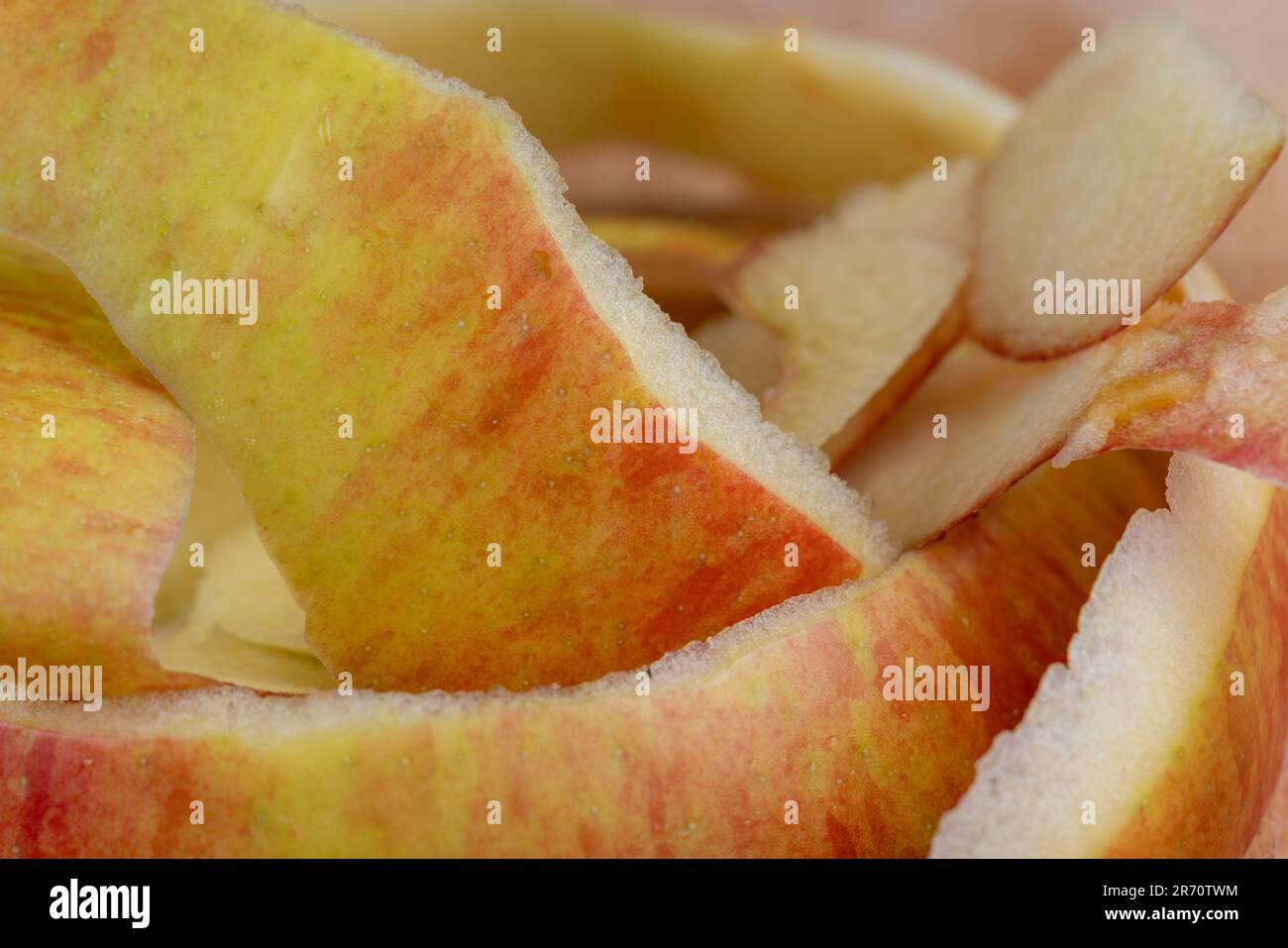 peeled red apple , the peel of a peeled apple scattered on the board ...