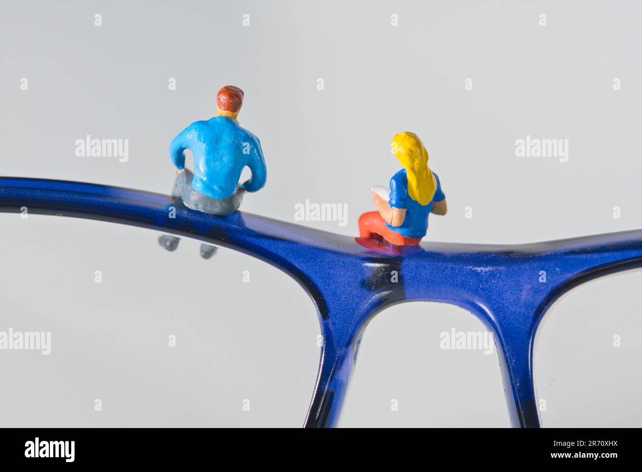 Two miniature figure people sitting on optical glasses Stock Photo - Alamy