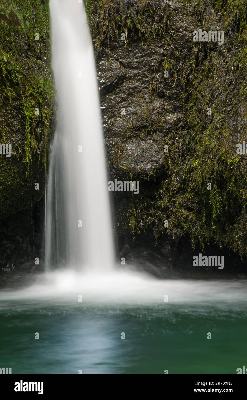 A picturesque waterfall cascading down a rocky cliff face into a deep ...