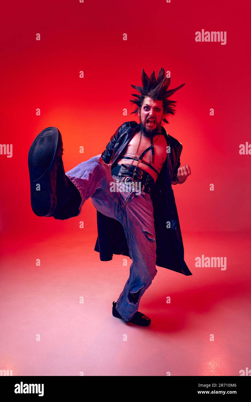 Emotional young man punk in extraordinary clothes, with makeup playing ...