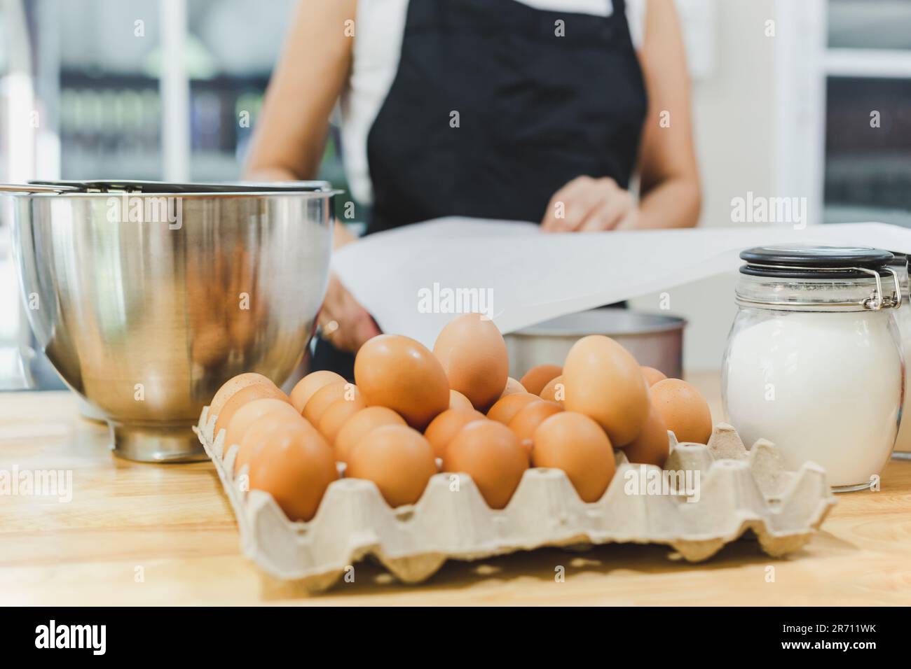 Chicken egg with Ingredients for baking on table with woman baker in ...