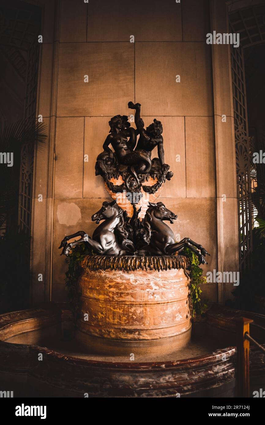 A statue of a human figure elegantly in front of a brick wall ...